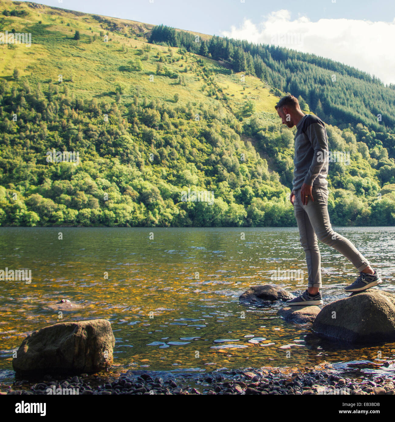 Man standing on rocks on riverbank, Scotland, UK Stock Photo - Alamy