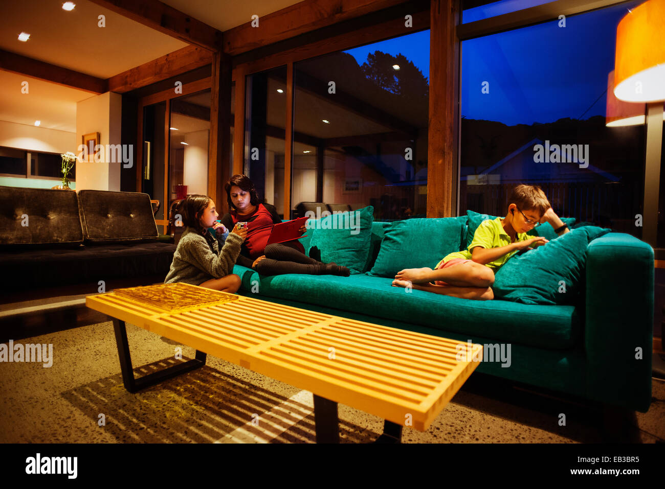 Mother and children relaxing together in modern living room Stock Photo ...