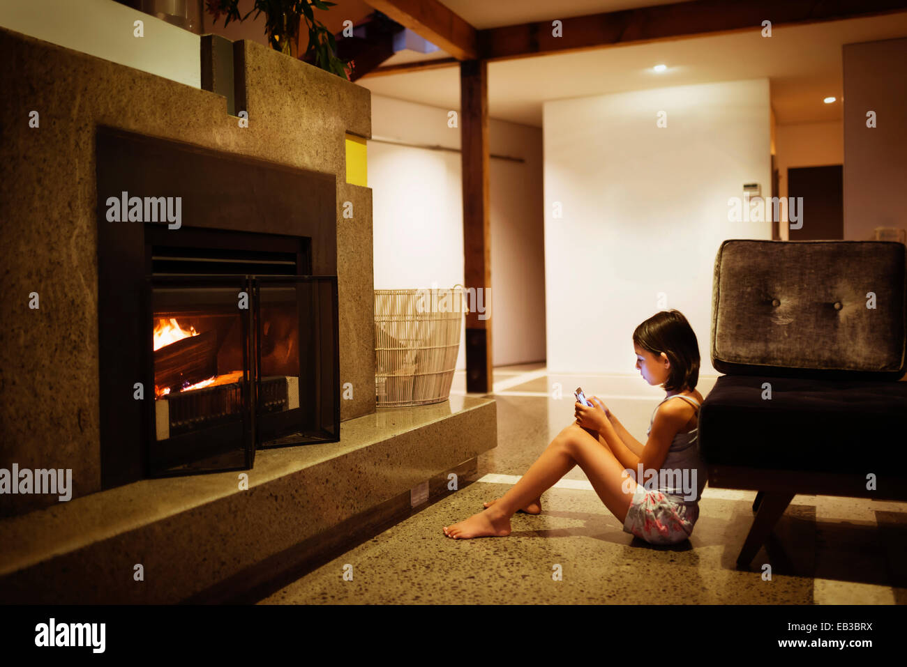 Mixed race girl using cell phone near fireplace in living room Stock ...