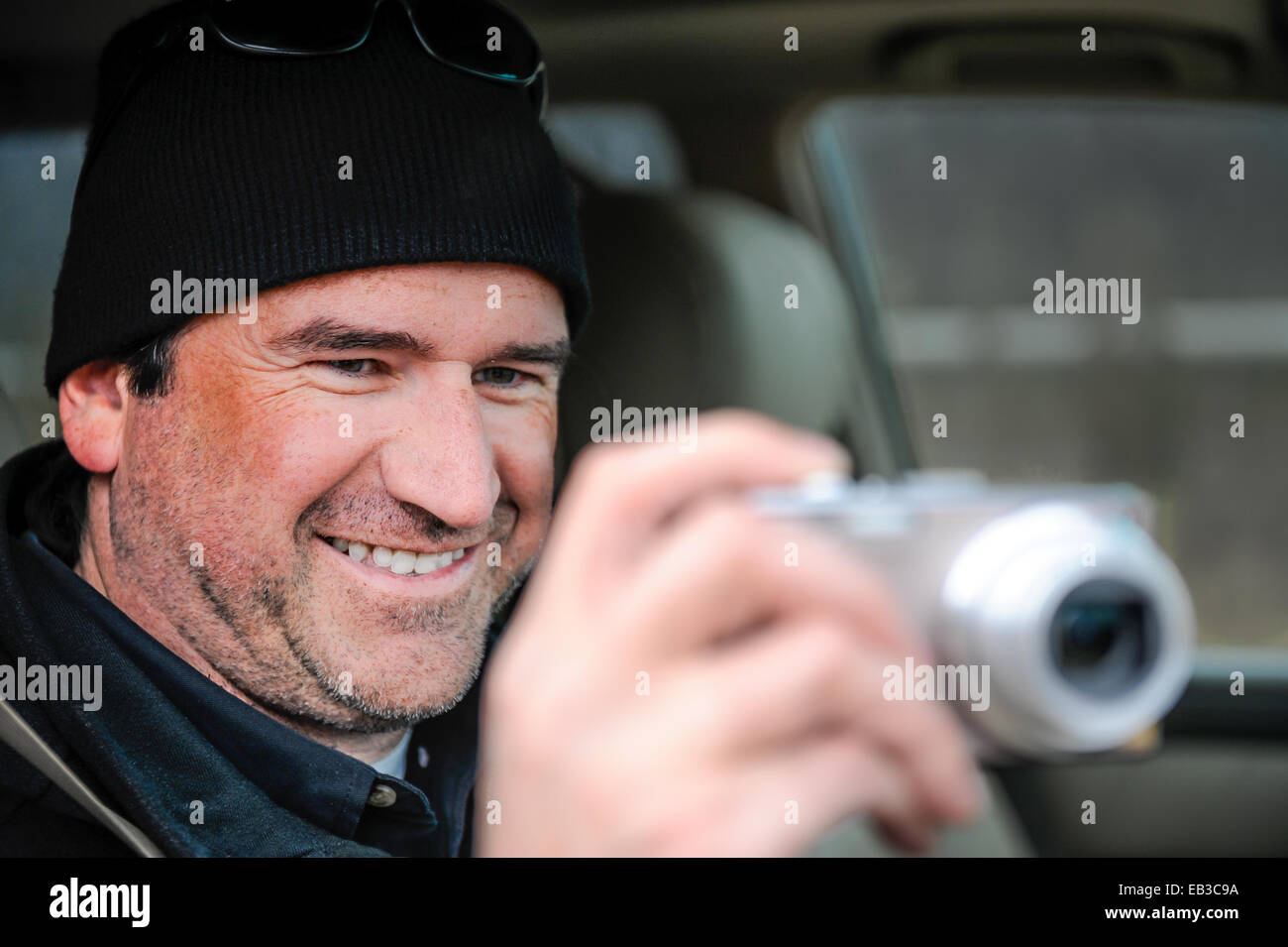 Smiling man taking photo through his car window Stock Photo - Alamy