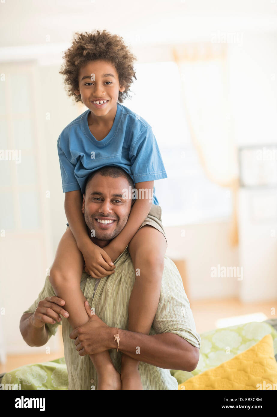 Father carrying son on shoulders in living room Stock Photo - Alamy