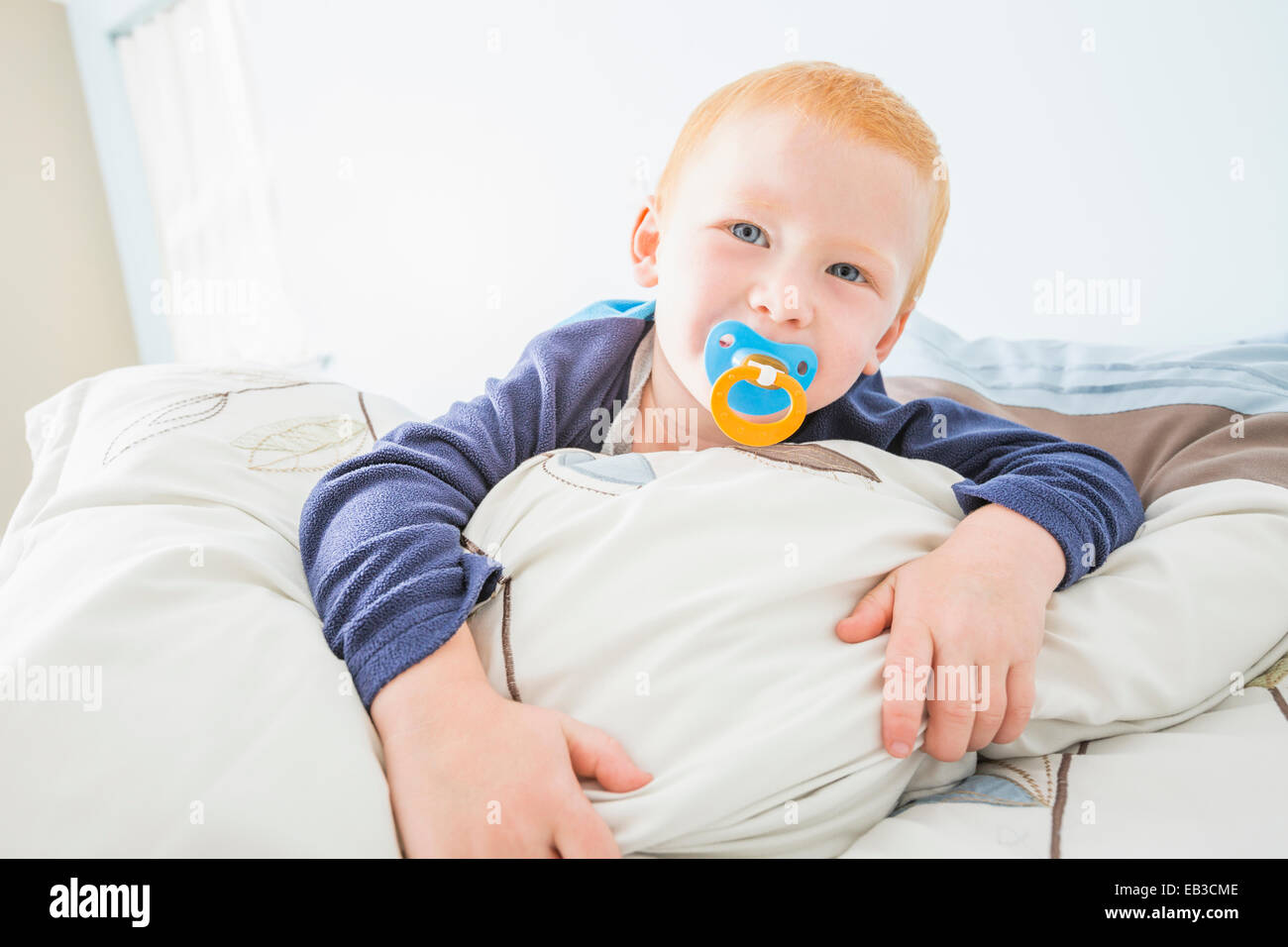 Caucasian boy sucking pacifier in bed Stock Photo - Alamy