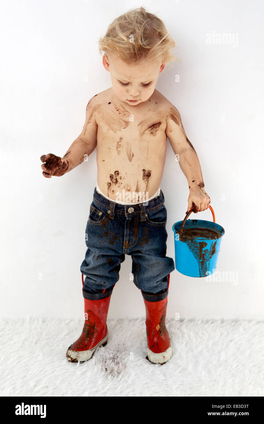 Messy Caucasian boy playing with mud on white carpet Stock Photo - Alamy