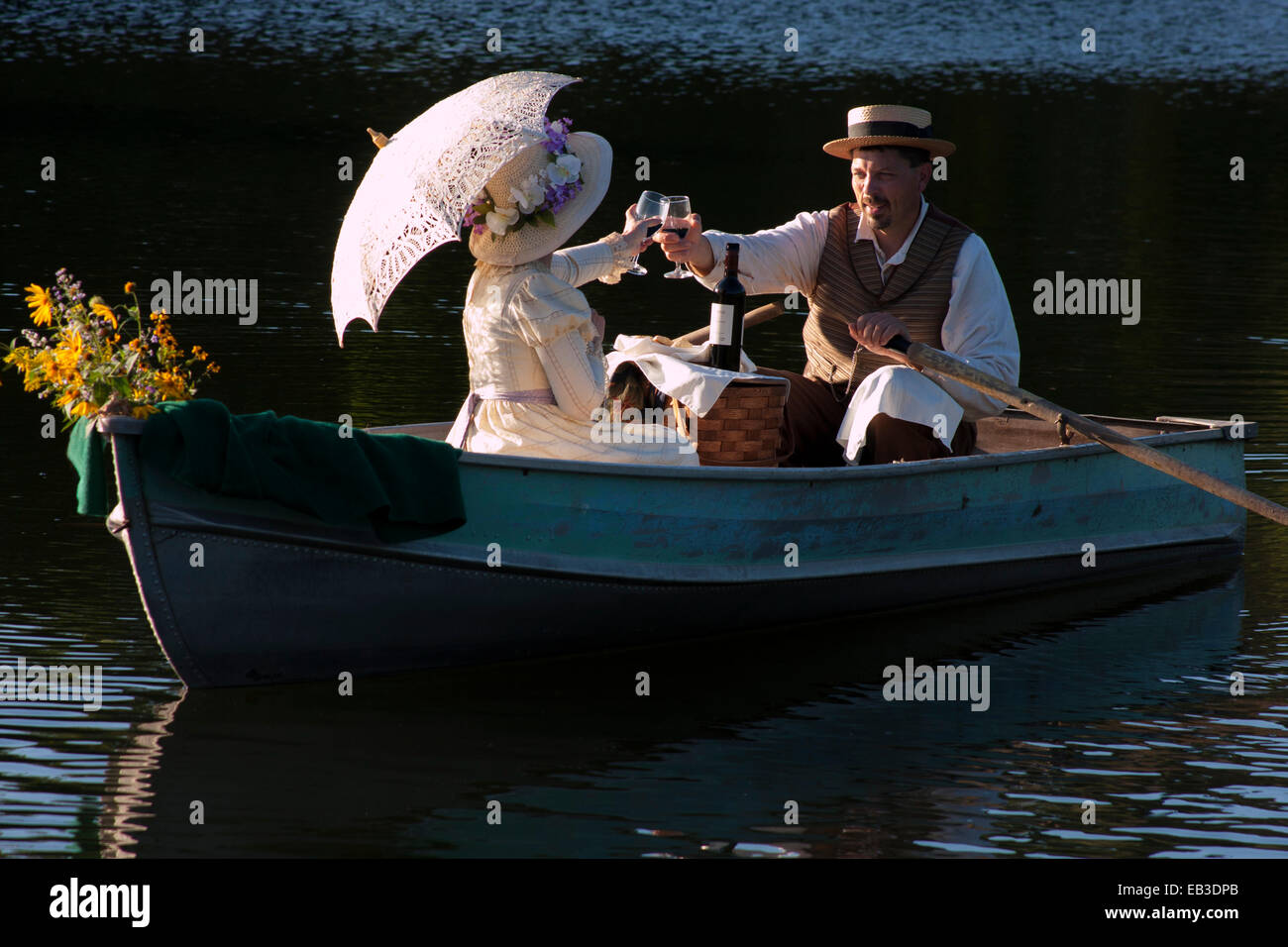 Victorian Couple in a rowboat at sunset toasting with wine glasses ...