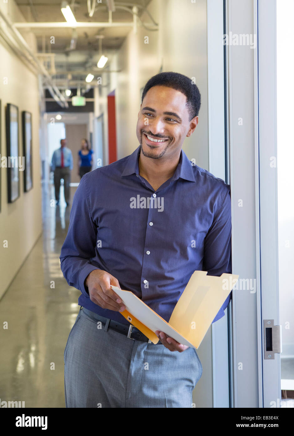 Black businessman holding folder in office hallway Stock Photo - Alamy