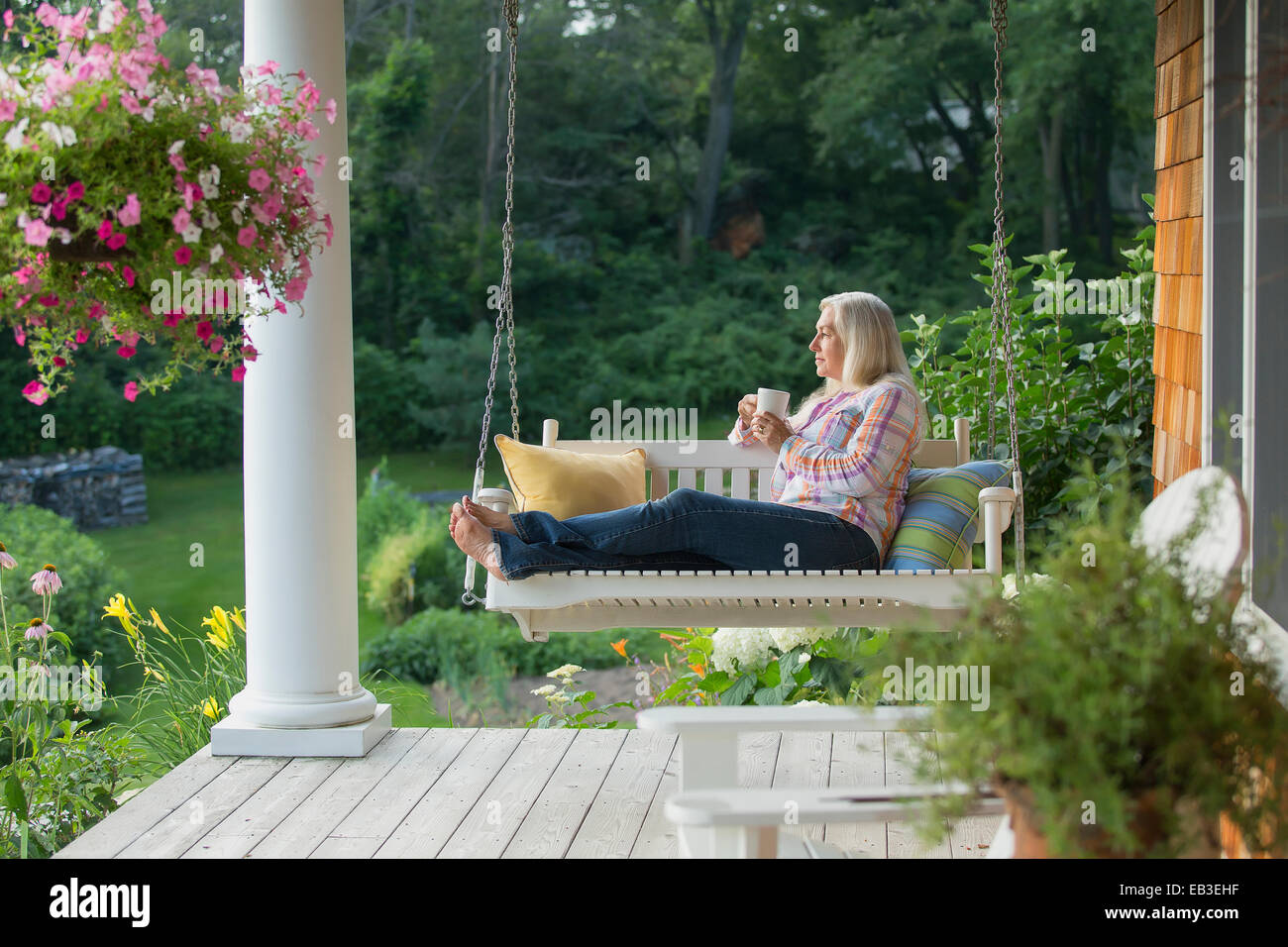 Older Caucasian woman drinking cup of coffee on porch swing Stock Photo ...