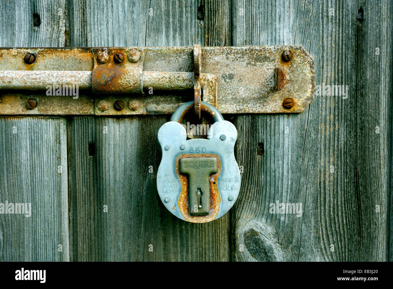 OLD PADLOCK MADE FROM METAL LOCKING AN OLD BOLT ON A WOODEN DOOR Stock ...