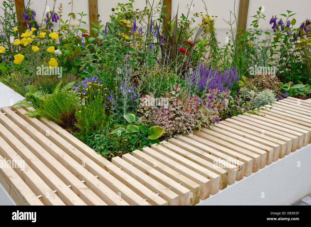 A raised flower border with bench seating in a public urban garden ...