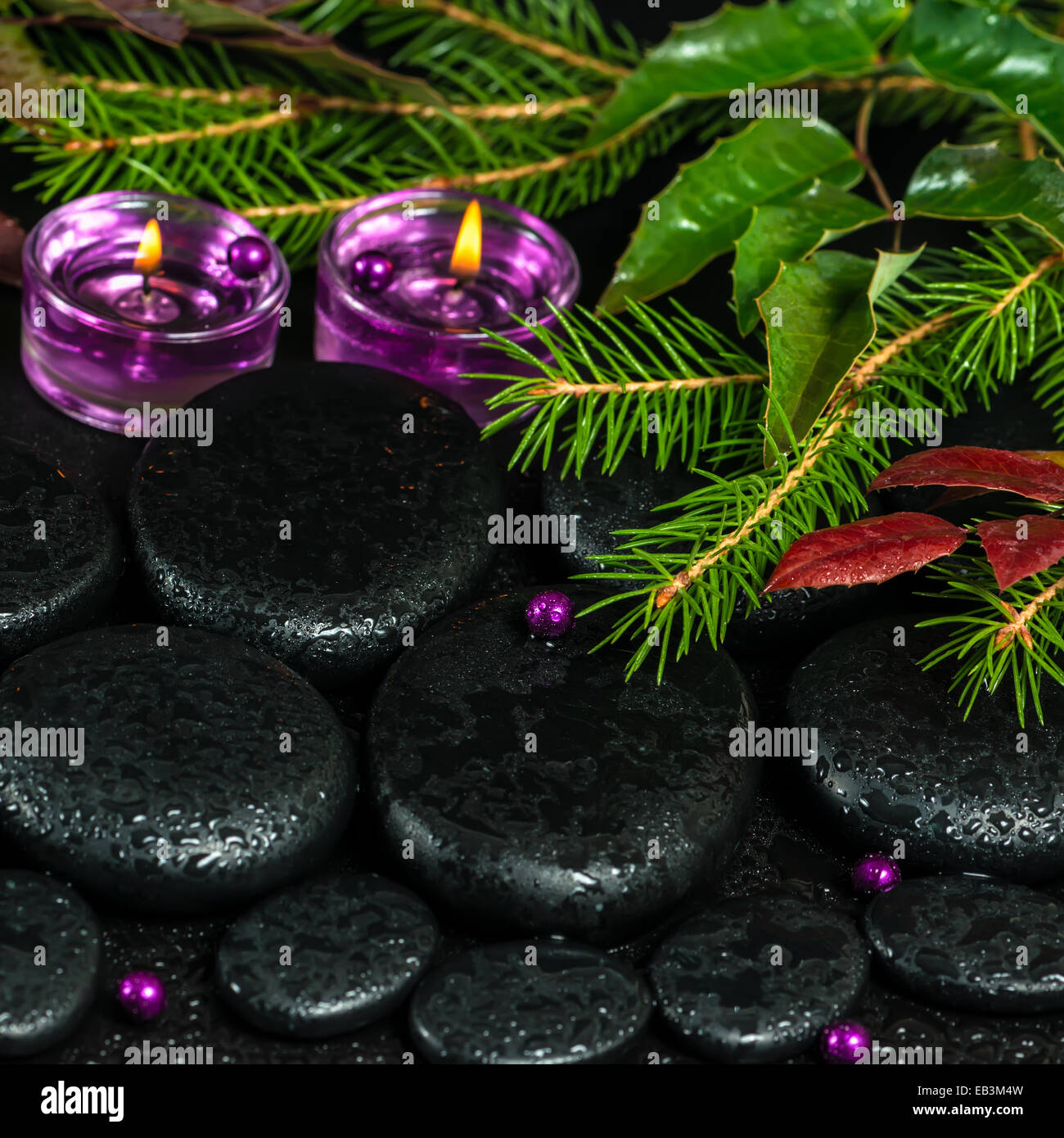 winter spa concept of zen basalt stones with drops, lilac candles and ...