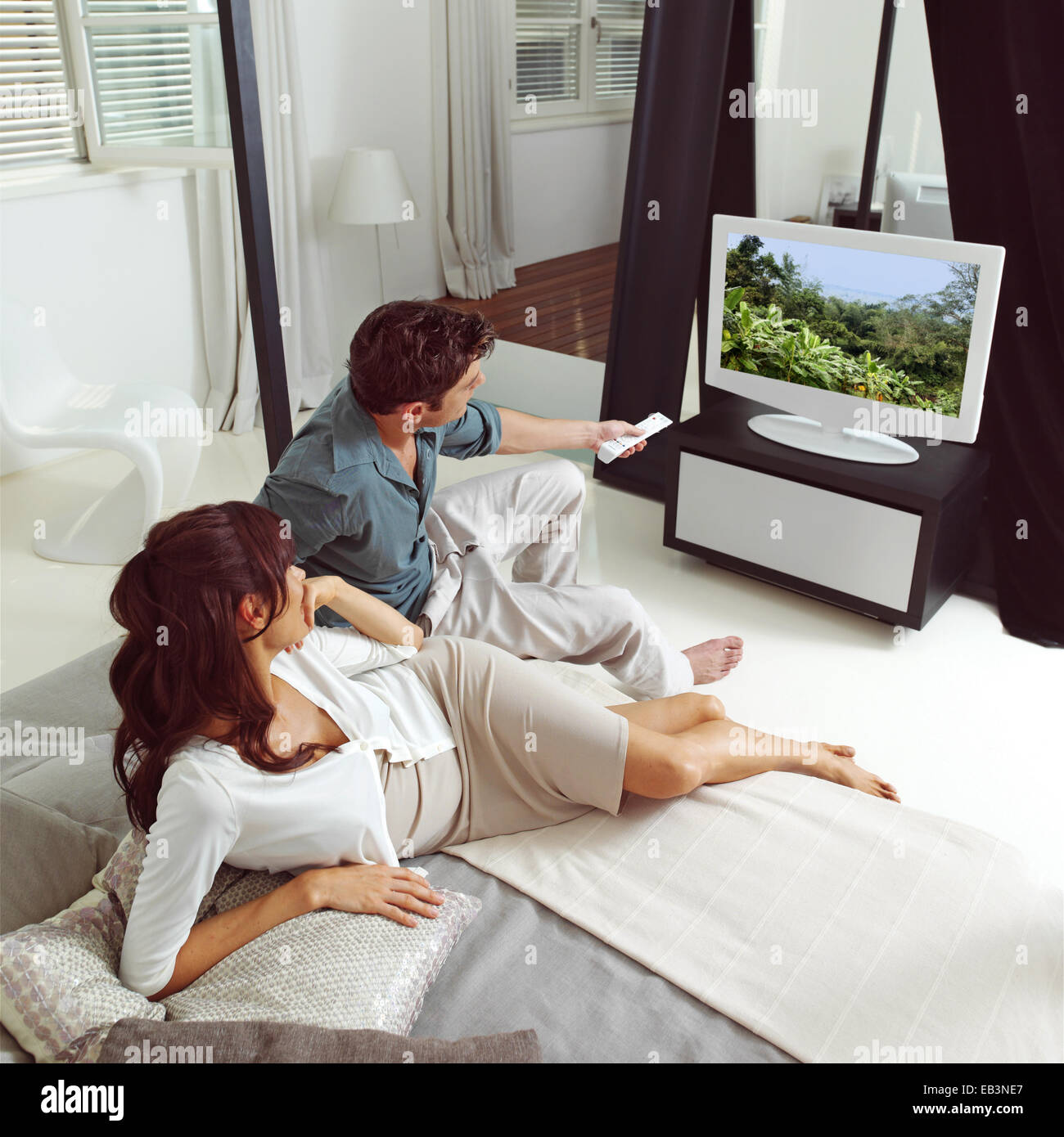 Happy young couple watching television together at home Stock Photo - Alamy