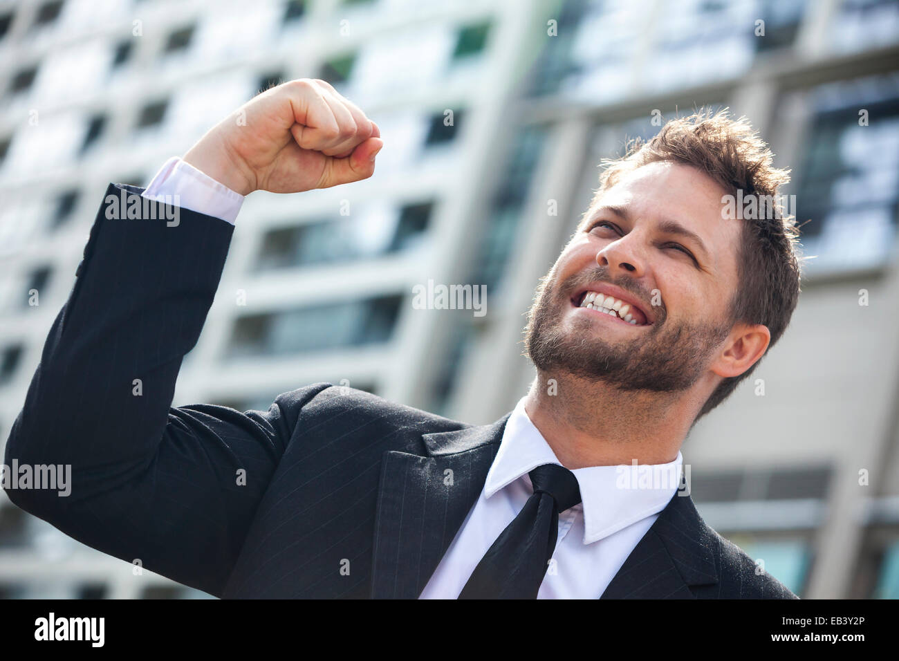 A young successful man, male executive businessman arms raised ...