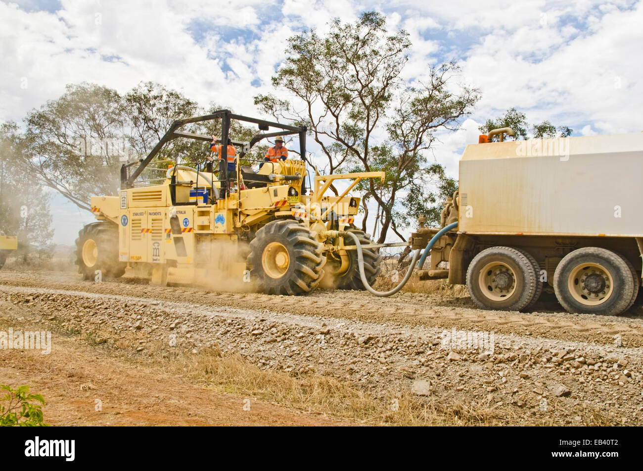 Road building. Water truck preceding a stabilizer Stock Photo - Alamy