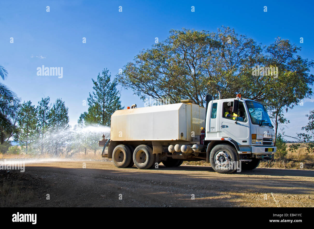 Road building. Truck spreading water for following heavy roller Stock ...