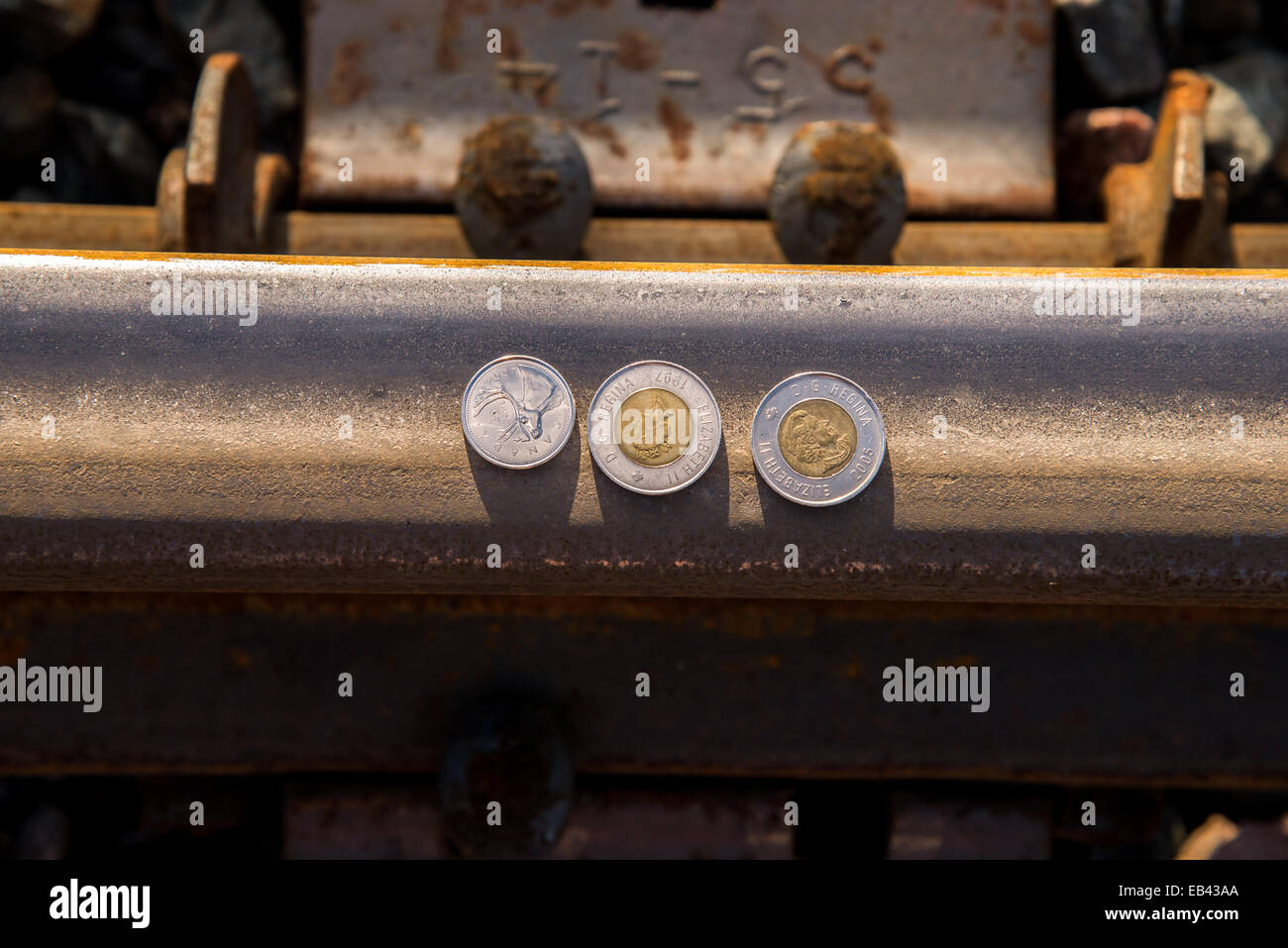 Three coins on a rail track. One quarter and two 2 dollar coins. The 2 ...