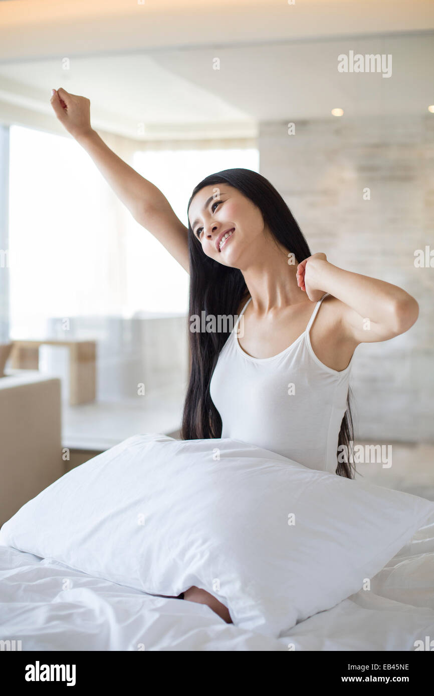 Young woman stretching in bed Stock Photo - Alamy