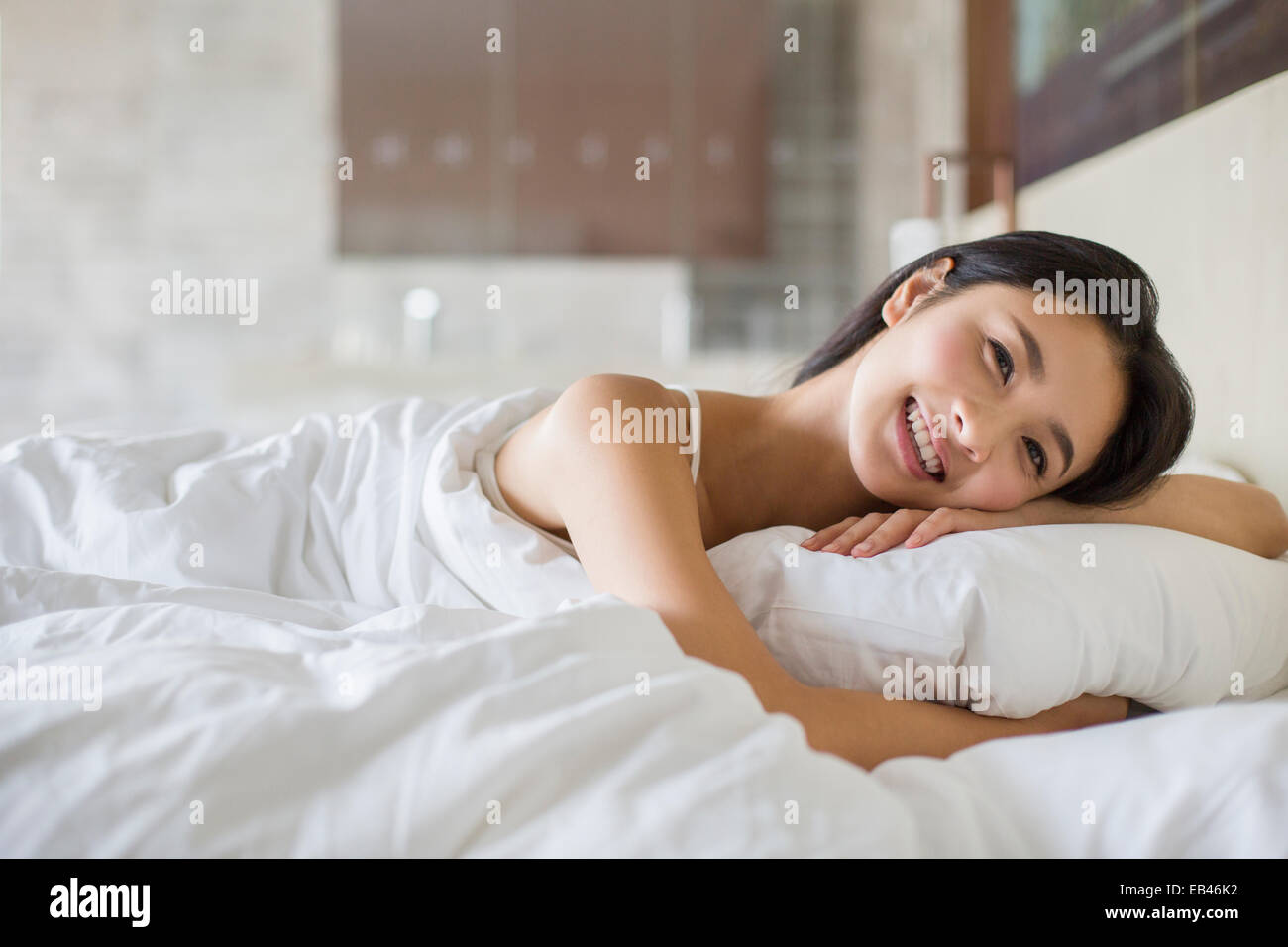 Young woman lying on bed Stock Photo - Alamy