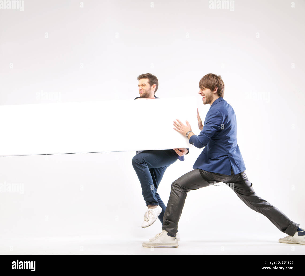 Two cheerful friends trying to push the banner Stock Photo - Alamy