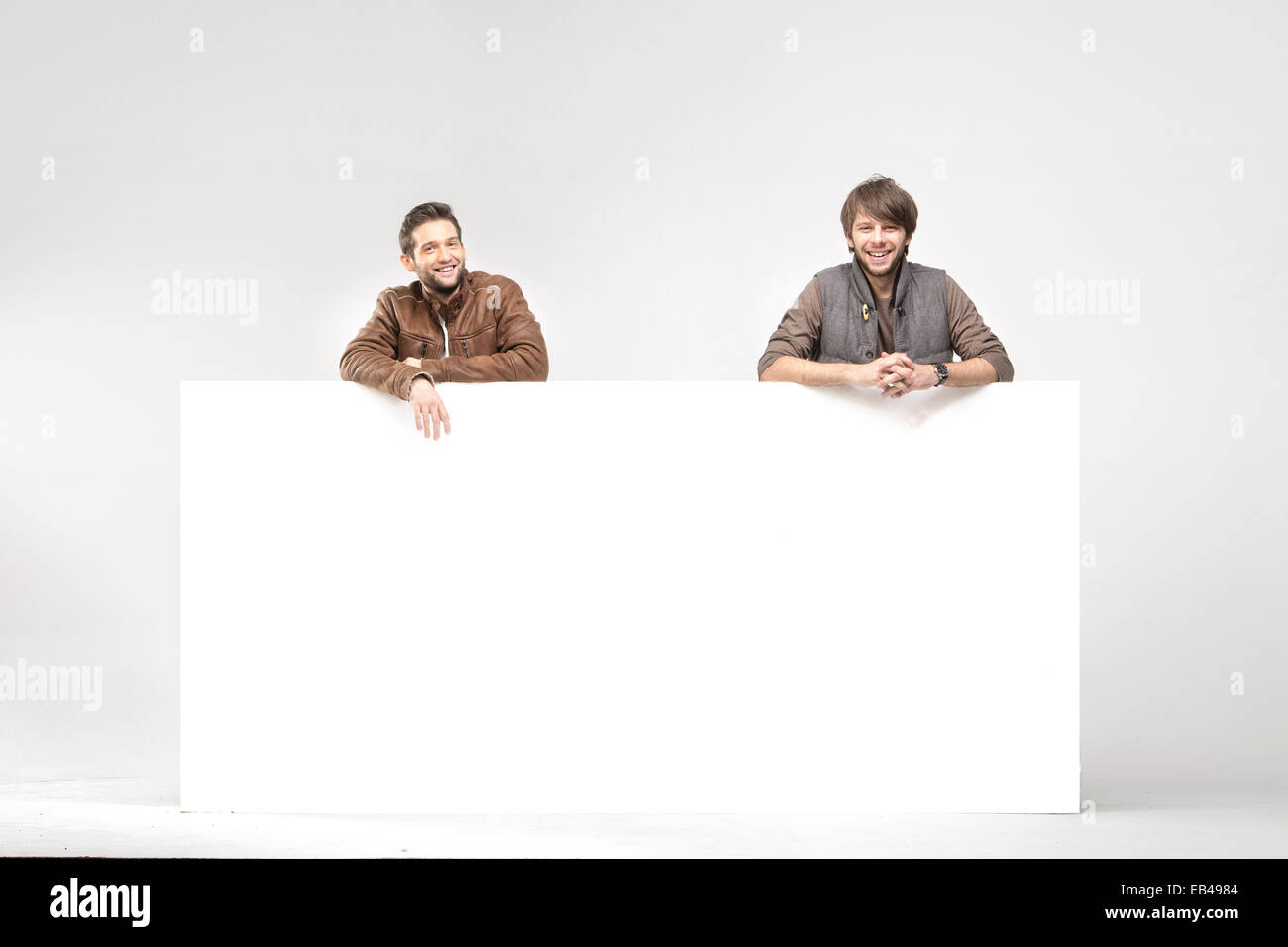 Two smiling guys with huge billboard Stock Photo - Alamy