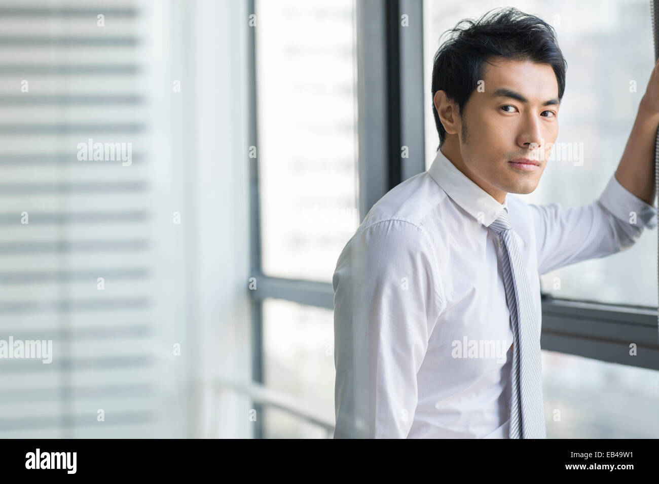 Young businessman standing by window Stock Photo - Alamy