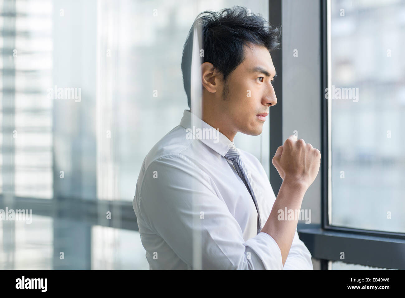 Young businessman looking through window Stock Photo - Alamy