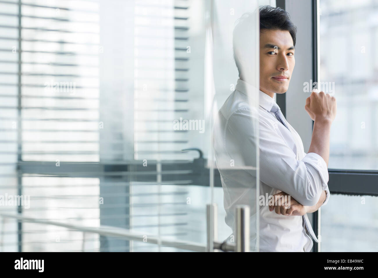 Young businessman standing by window Stock Photo - Alamy