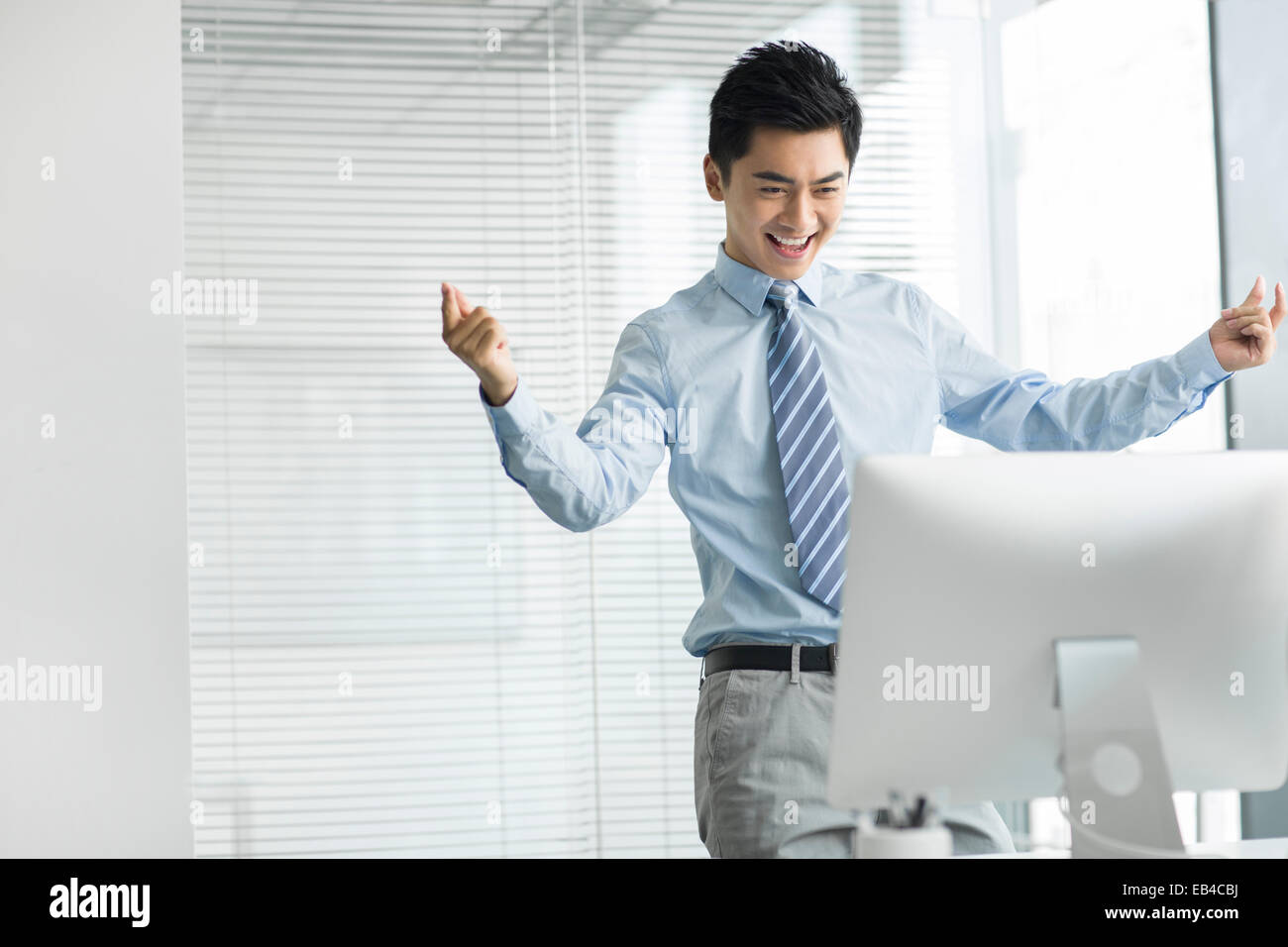 Cheerful young businessman using computer in office Stock Photo - Alamy