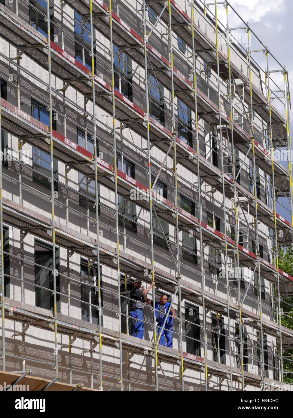 Construction workers at work standing on metal scaffolding structure ...