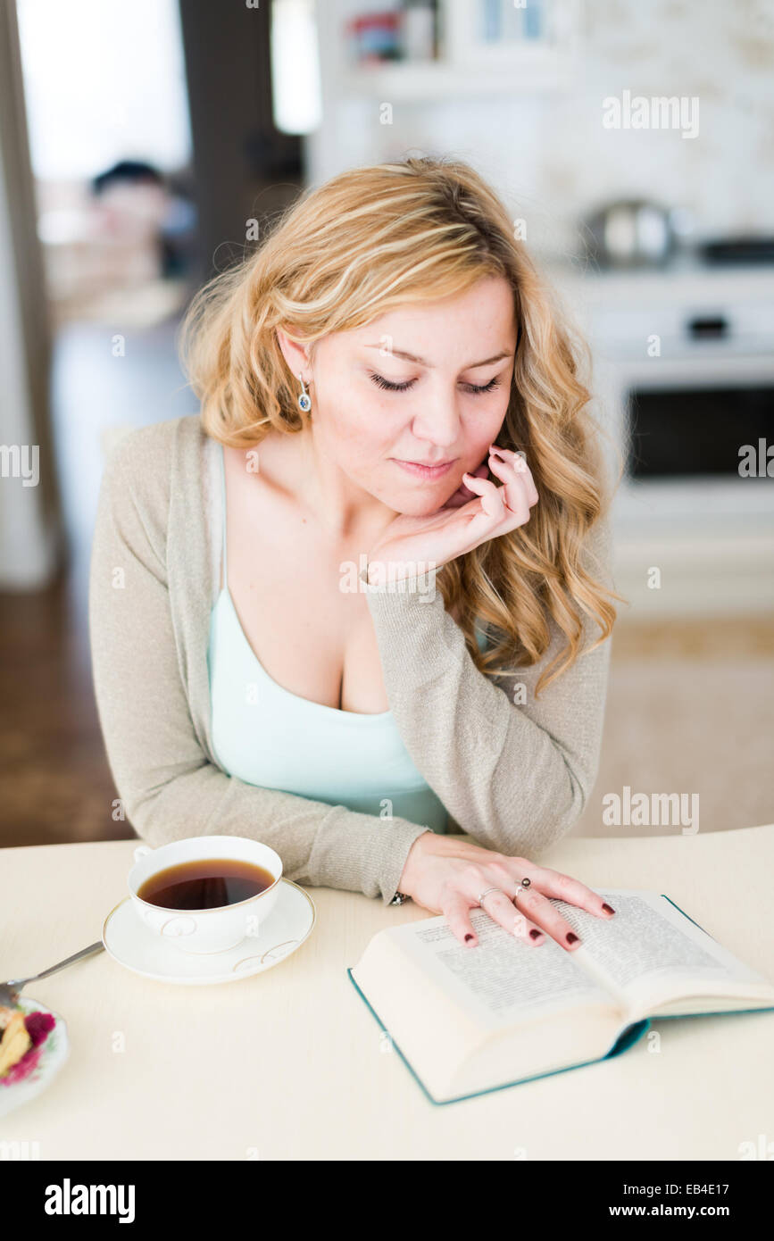 Lady reads an interesting book and drinks coffee Stock Photo - Alamy