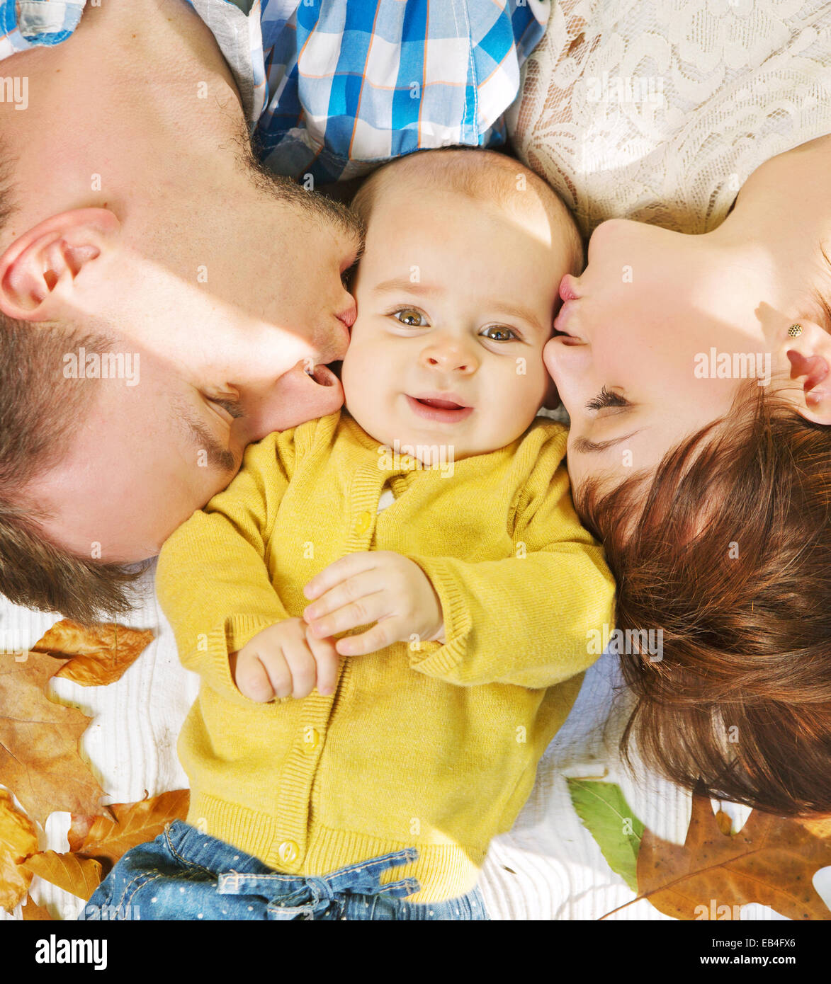 Parents hugging and kissing baby Stock Photo - Alamy