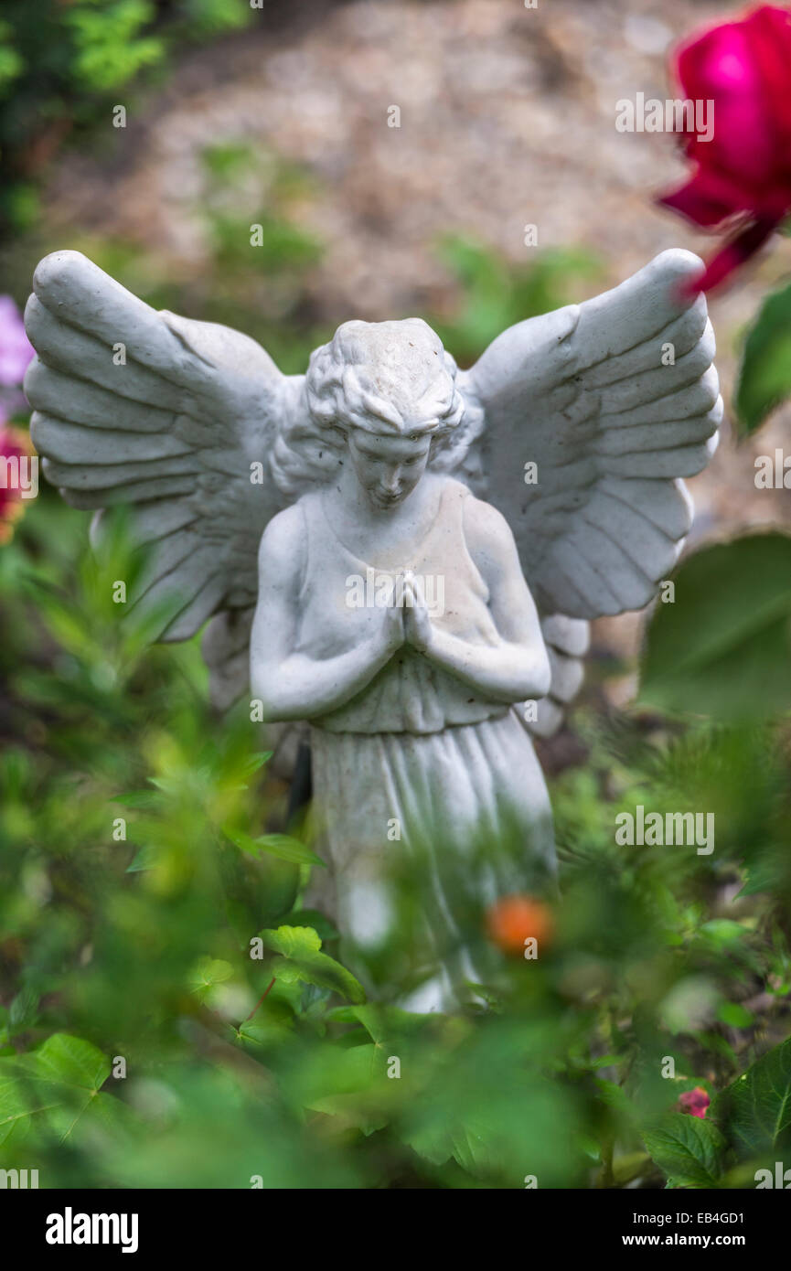 Stone angel figurine in a graveyard wings spread praying for the soul ...