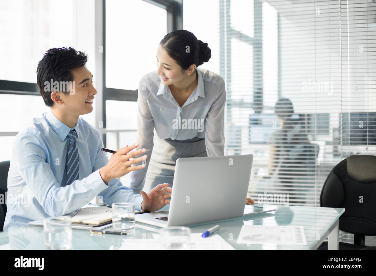 Young businesswoman and businessman talking in office Stock Photo - Alamy