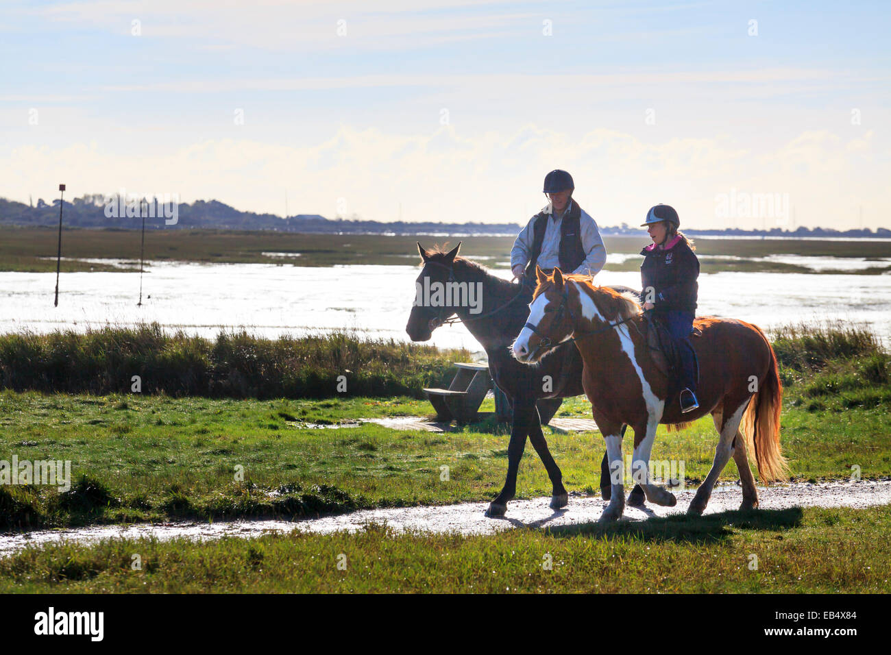 Two horse riders riding on path by sea Stock Photo - Alamy