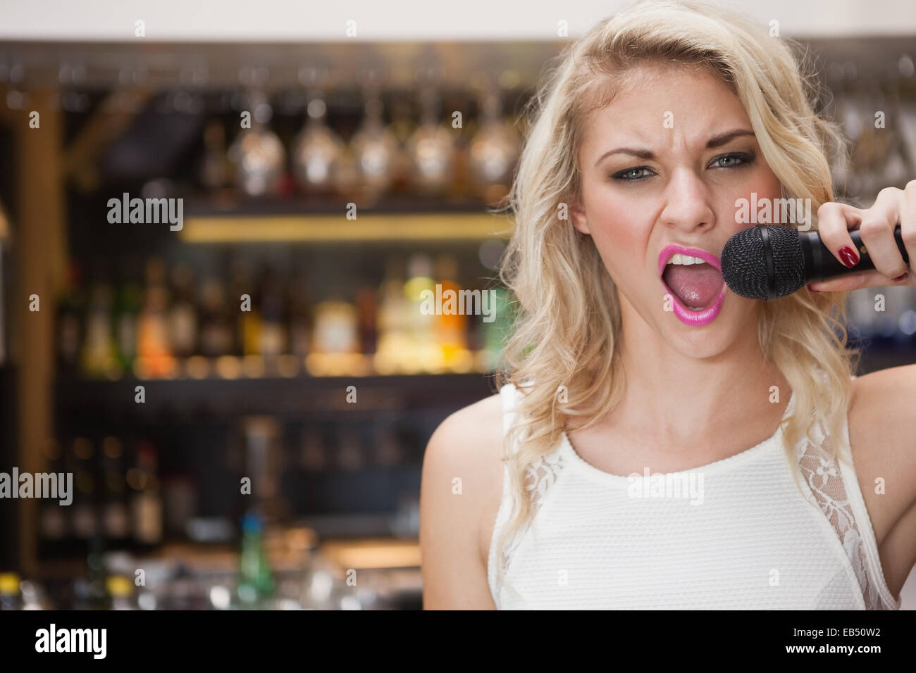 Pretty blonde singing with her microphone Stock Photo - Alamy