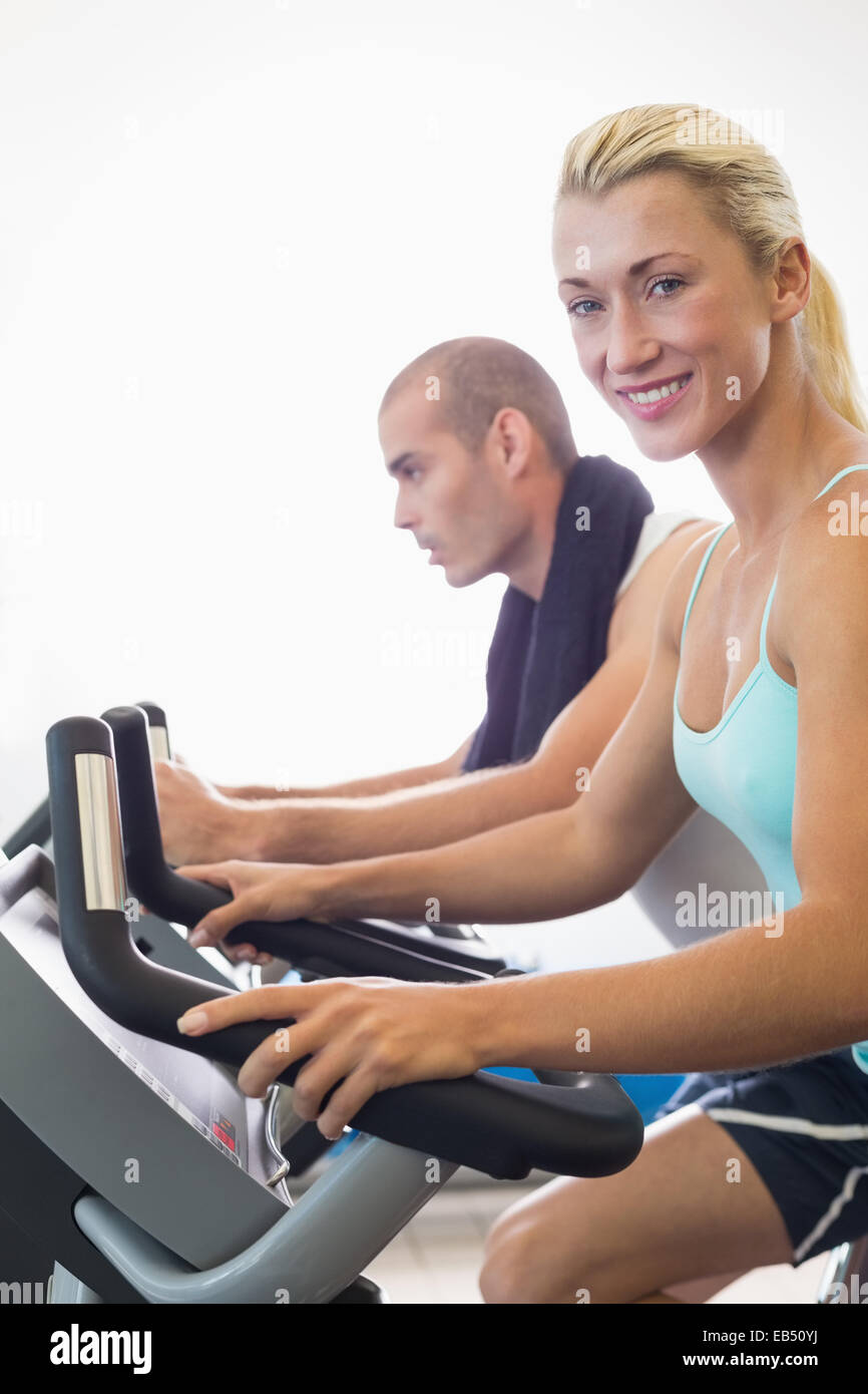 Fit couple working on exercise bikes at gym Stock Photo - Alamy