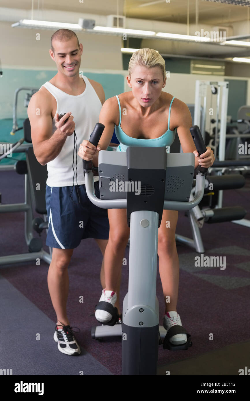 Trainer timing his client on exercise bike at gym Stock Photo - Alamy