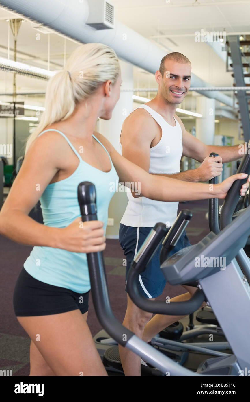 Fit young couple working on x-trainers at gym Stock Photo - Alamy