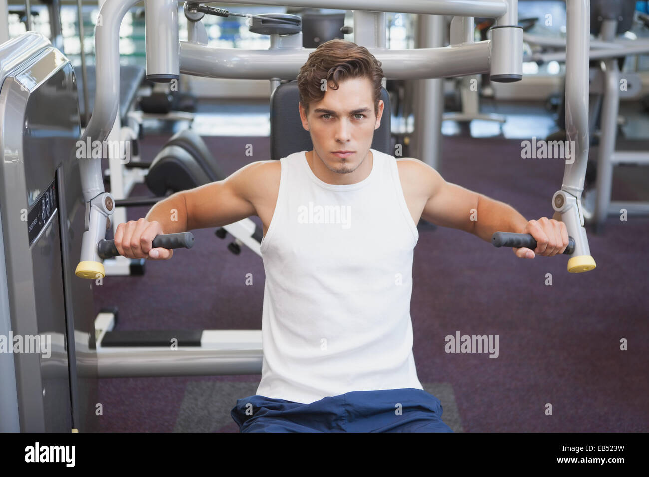 Fit man using weights machine for arms Stock Photo - Alamy