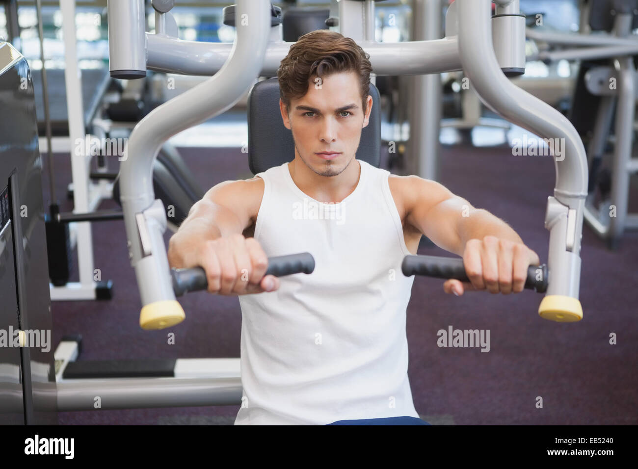 Fit man using weights machine for arms Stock Photo - Alamy