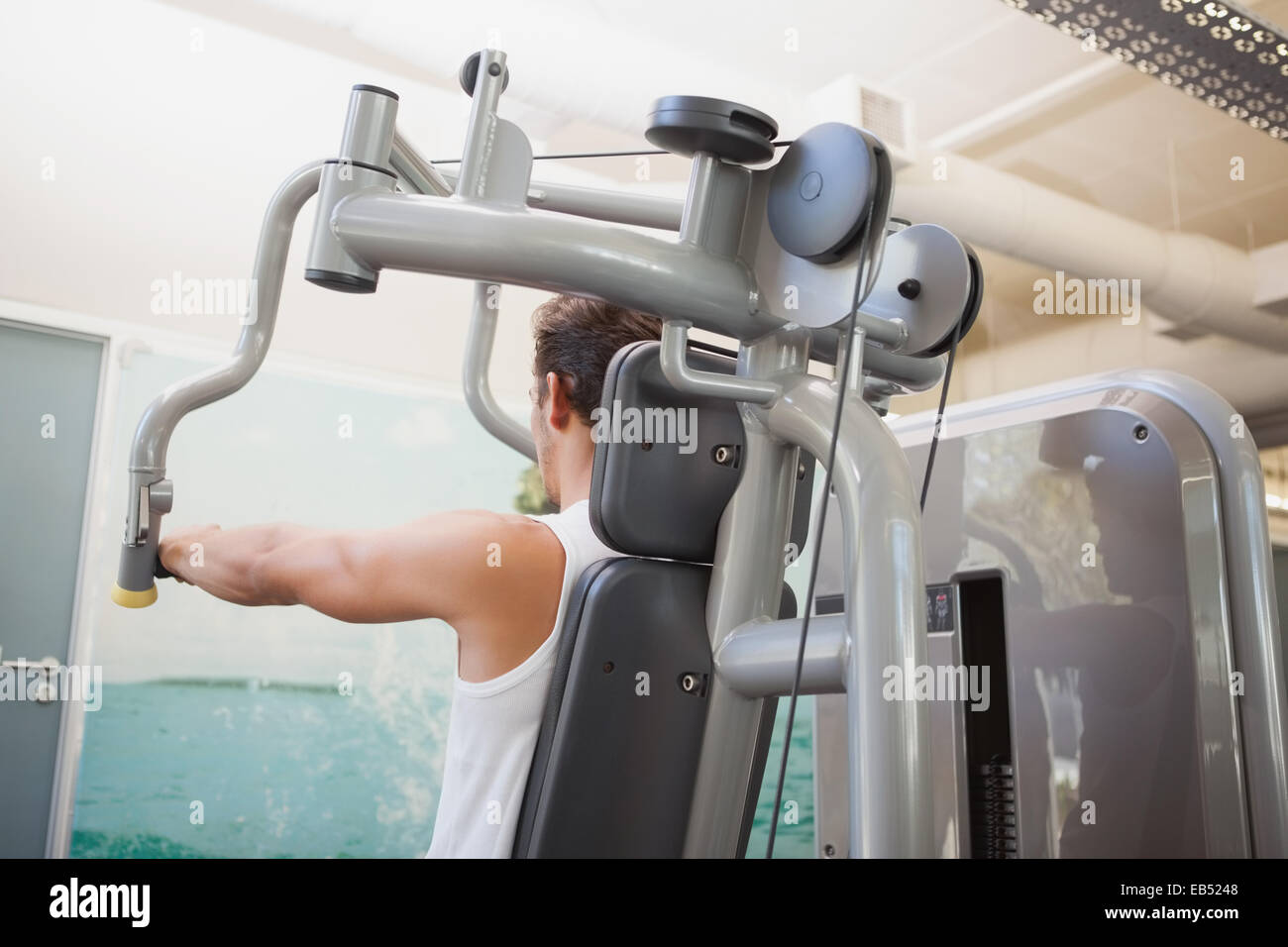 Fit man using weights machine for arms Stock Photo - Alamy