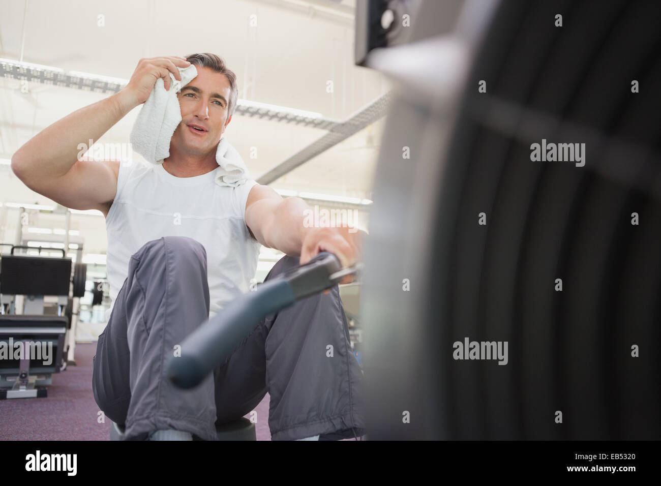 Fit man working out on rowing machine Stock Photo - Alamy