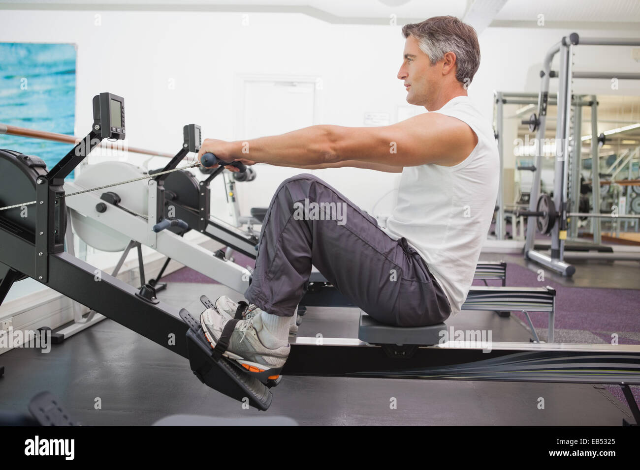 Fit man working out on rowing machine Stock Photo - Alamy