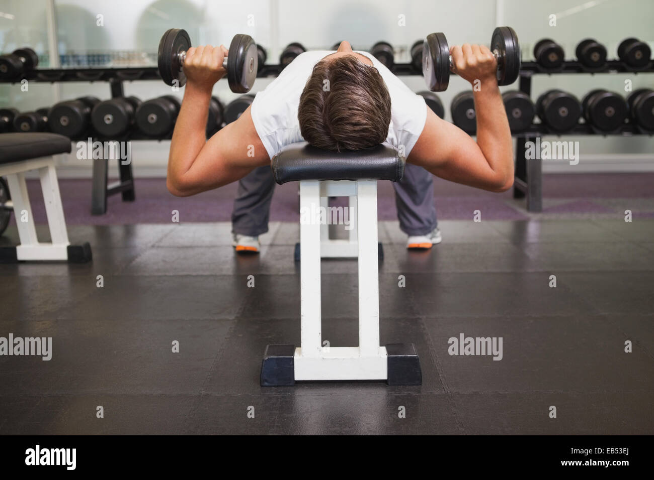 Fit man lifting dumbbells lying on the bench Stock Photo - Alamy