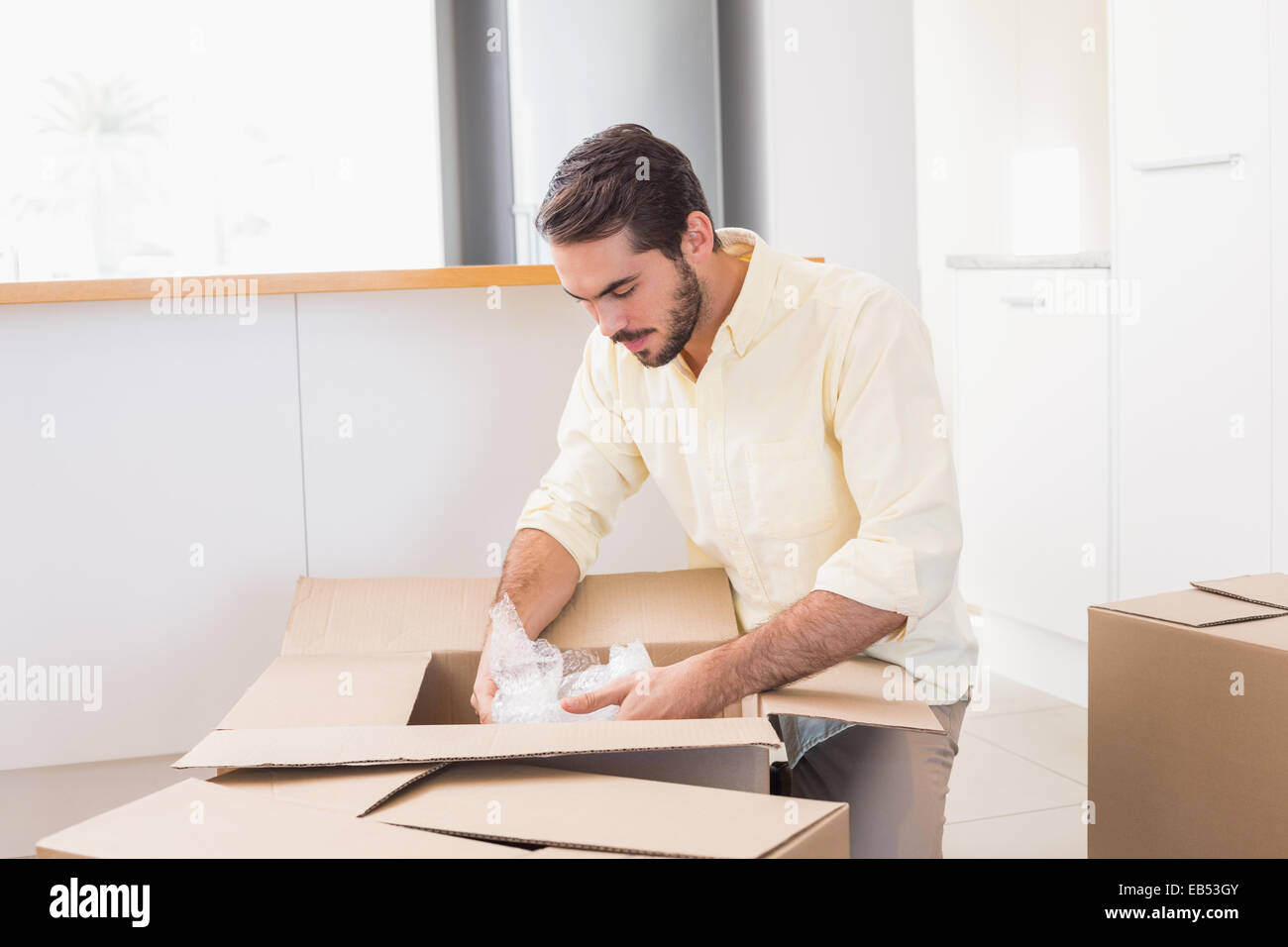 Young man unpacking boxes in kitchen Stock Photo - Alamy