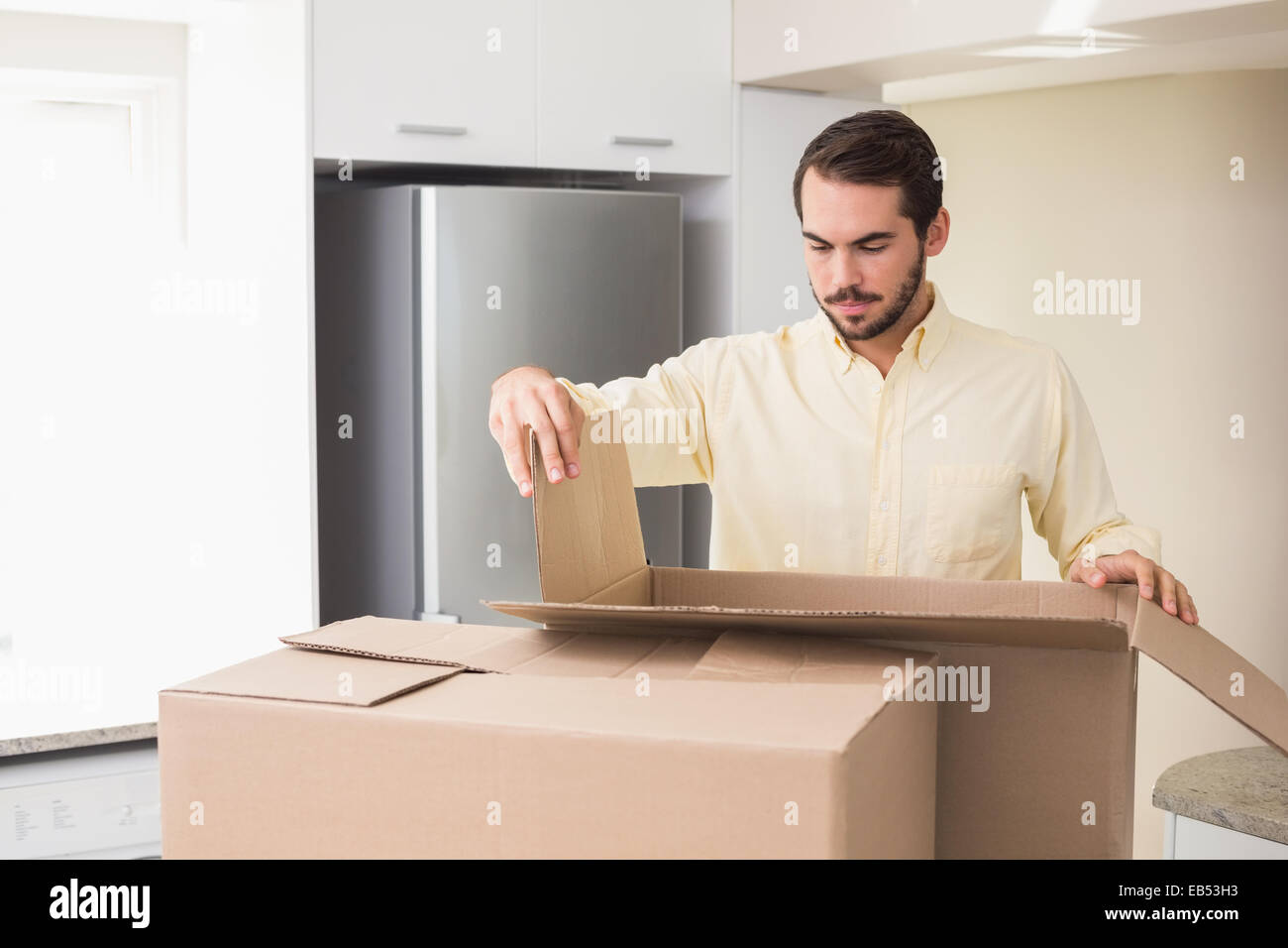 Young man unpacking boxes in kitchen Stock Photo - Alamy