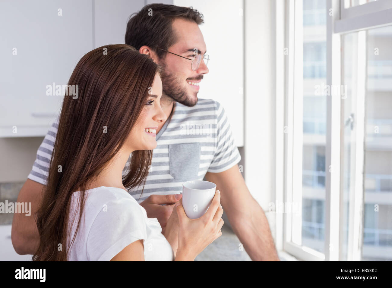 Young couple looking out their window Stock Photo - Alamy