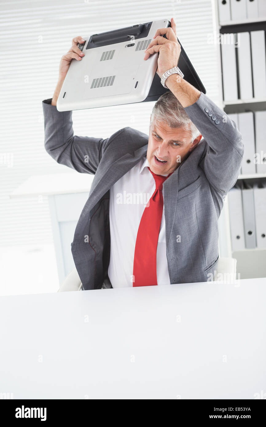 Angry businessman throwing his laptop Stock Photo - Alamy