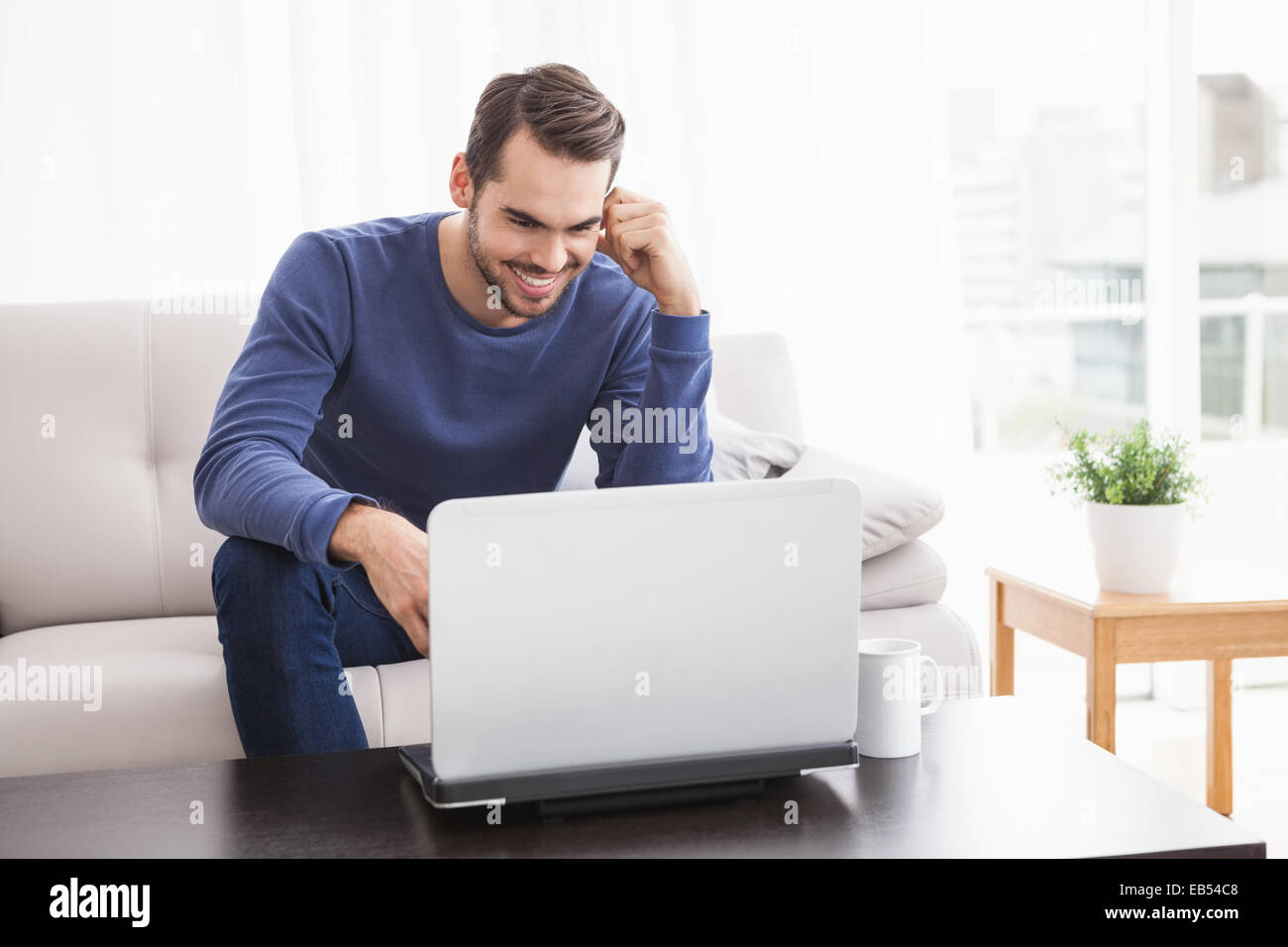 Smiling young man using his laptop Stock Photo - Alamy