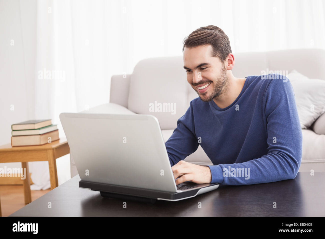 Smiling young man using his laptop Stock Photo - Alamy