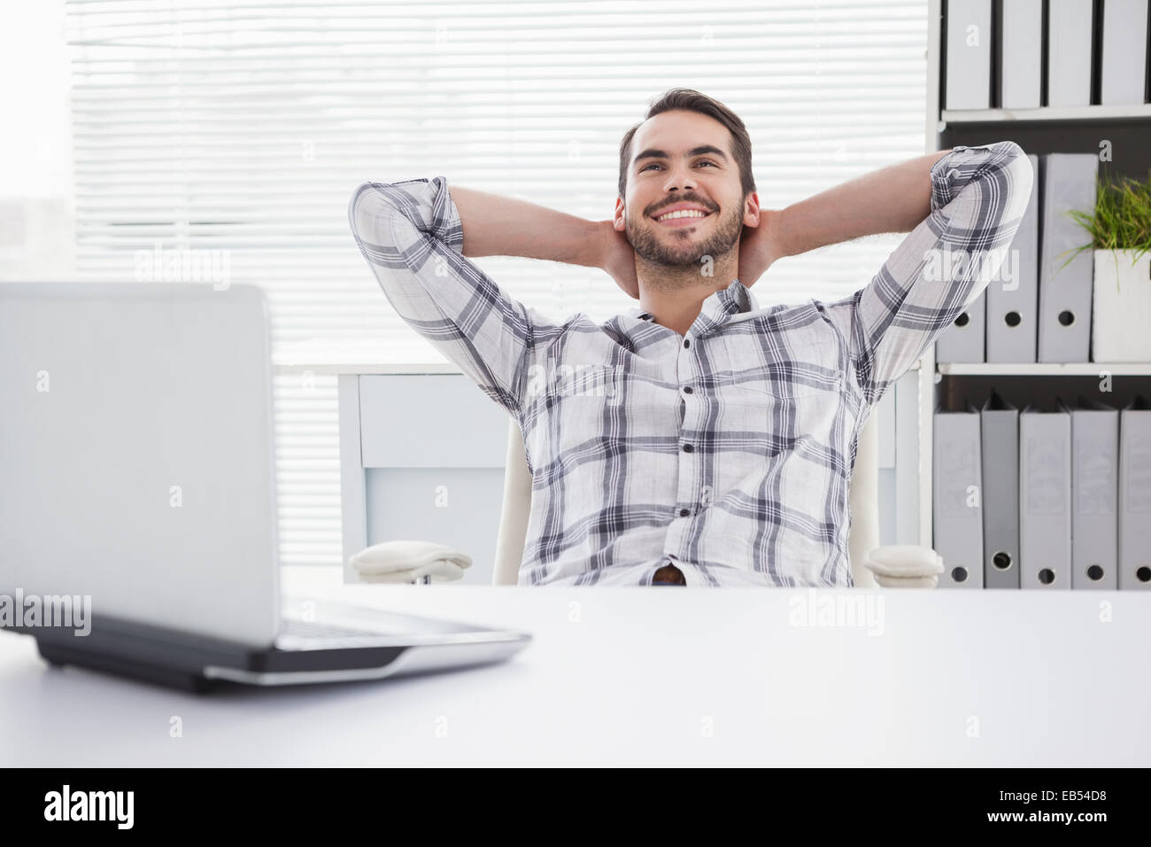 Casual businessman relaxing at desk leaning back Stock Photo - Alamy
