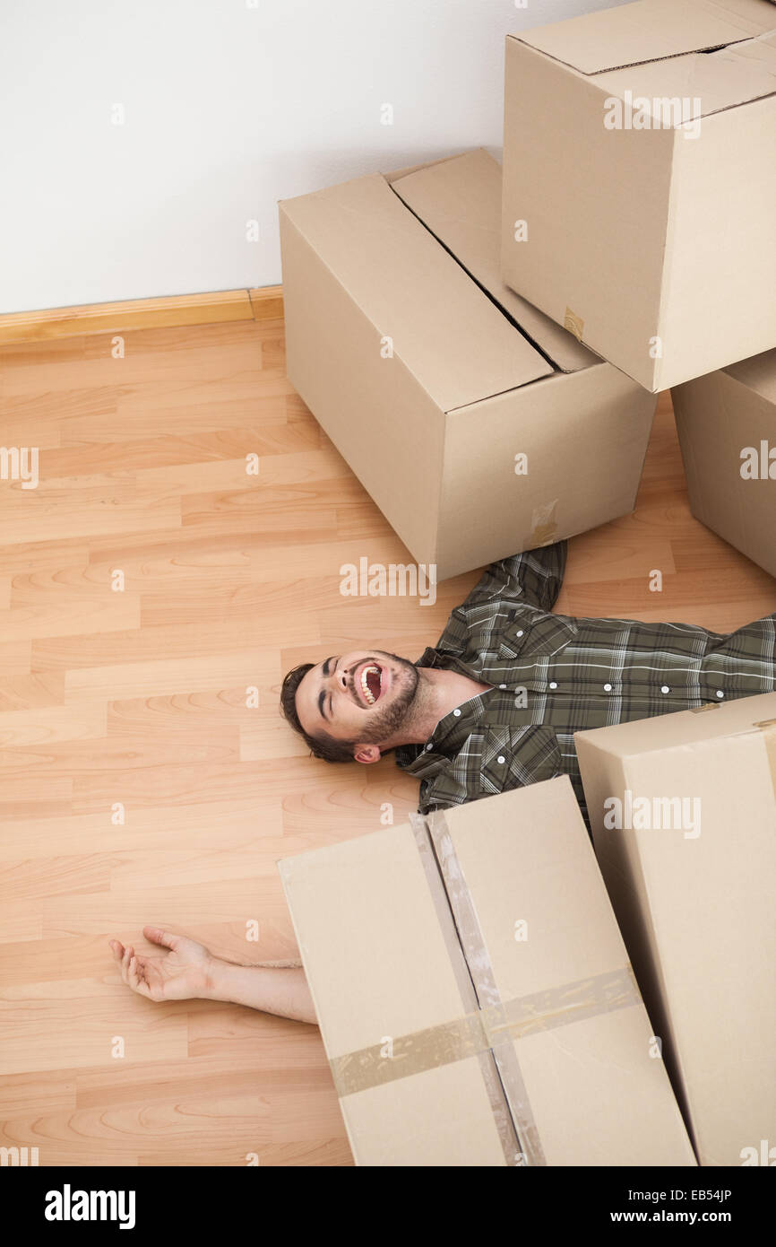 Man lying under fallen boxes Stock Photo - Alamy